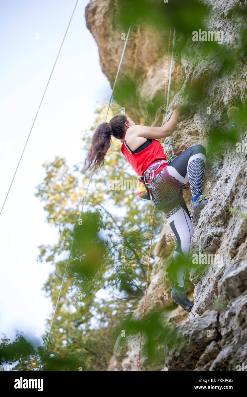 Photo of athlete girl clambering over rock against background of green ...