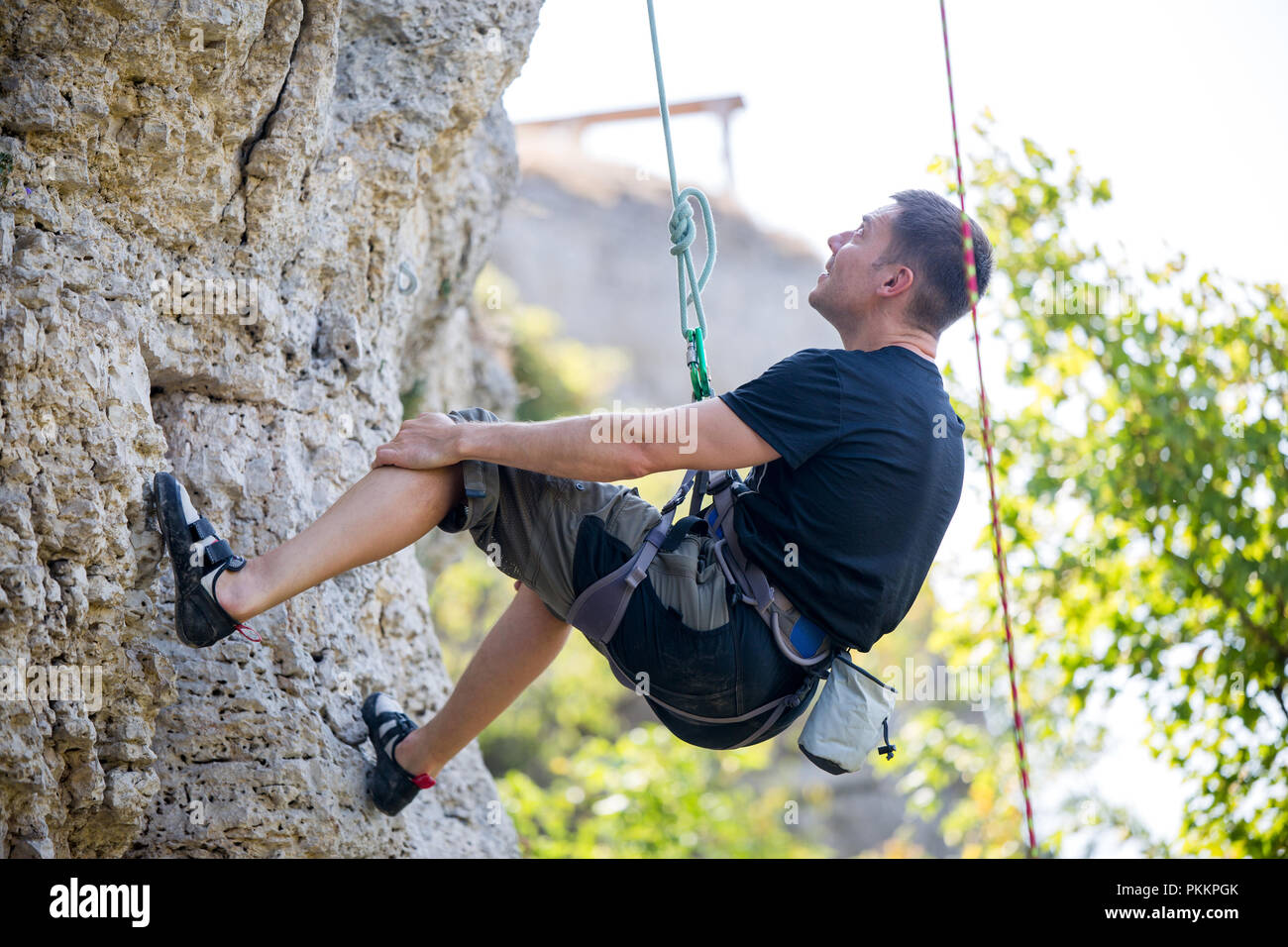 Photo of athlete man in helmet clambering over rock against background ...