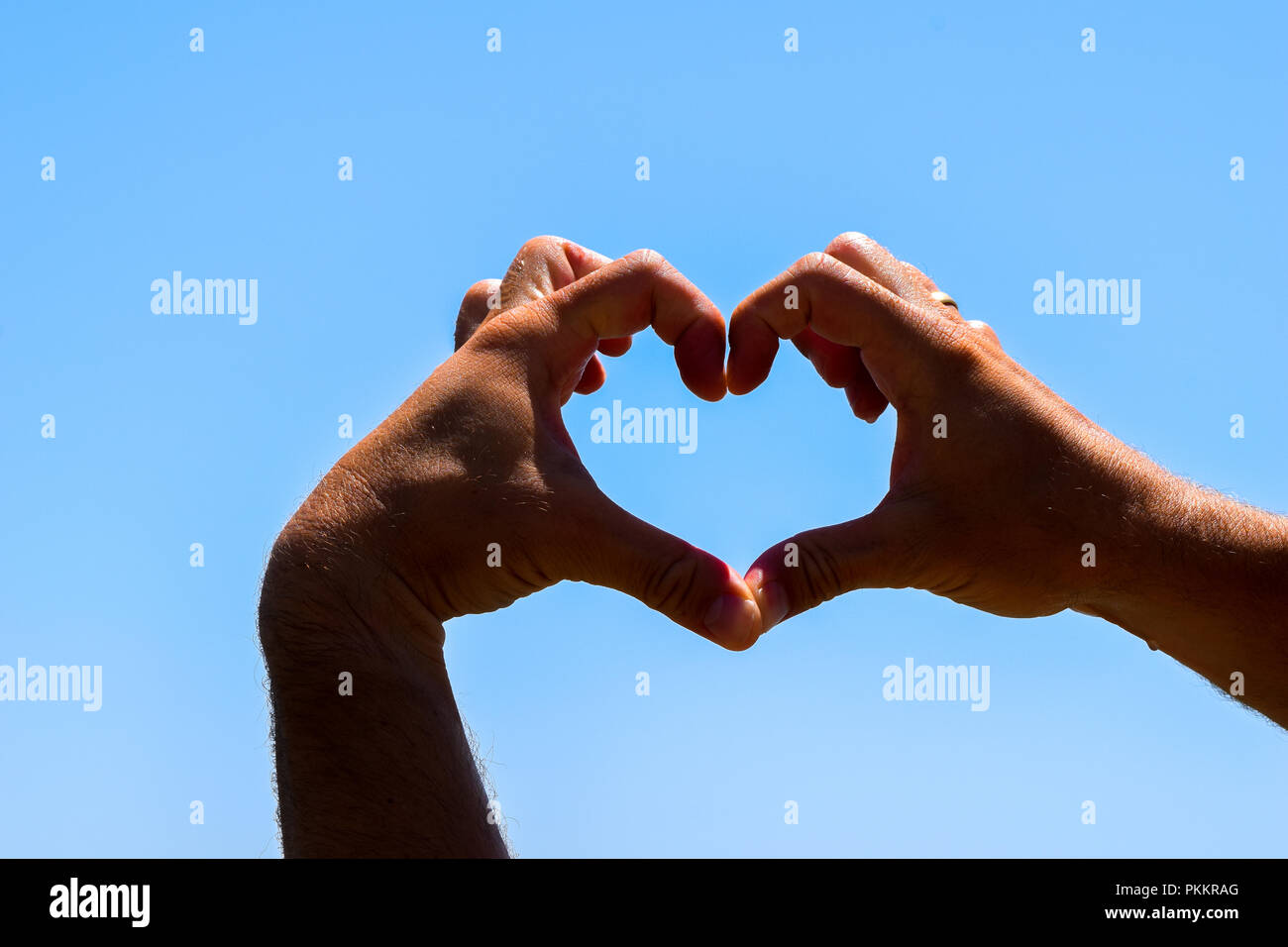 heart shape with man's hand in front of blue sky, love sing Stock Photo ...