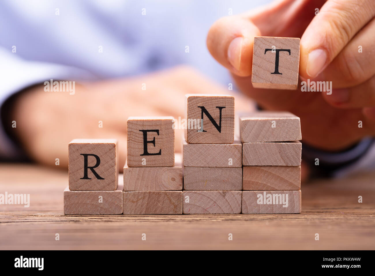 Person's Hand Holding Wooden Blocks Placing Last Alphabet Of Word Rent ...