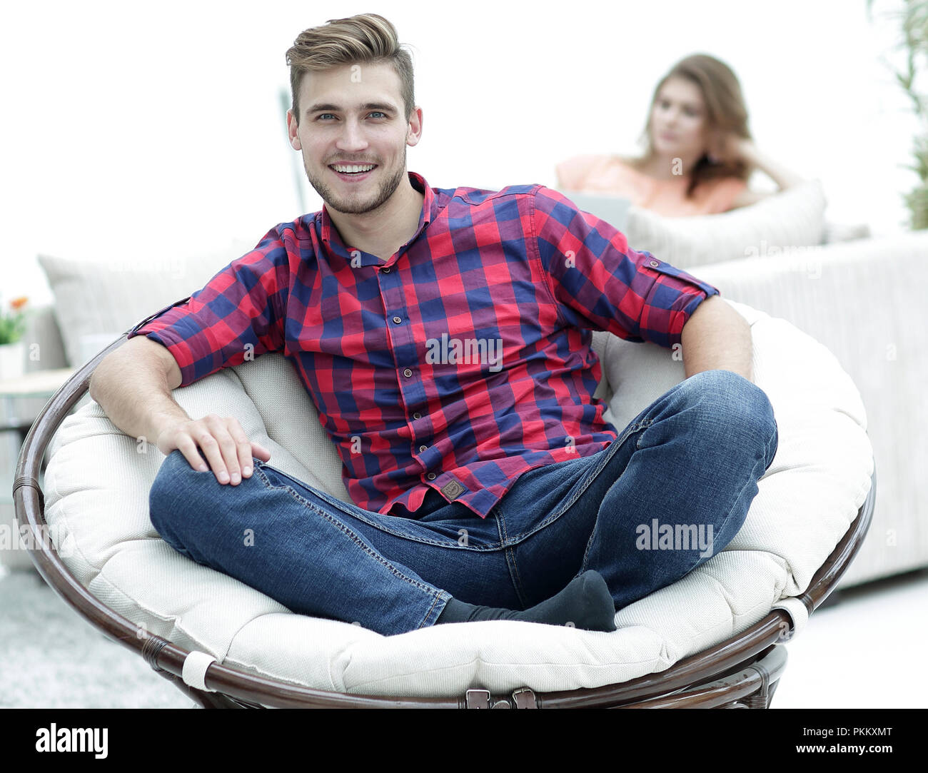 modern young man sitting in a big round chair on blurred background ...
