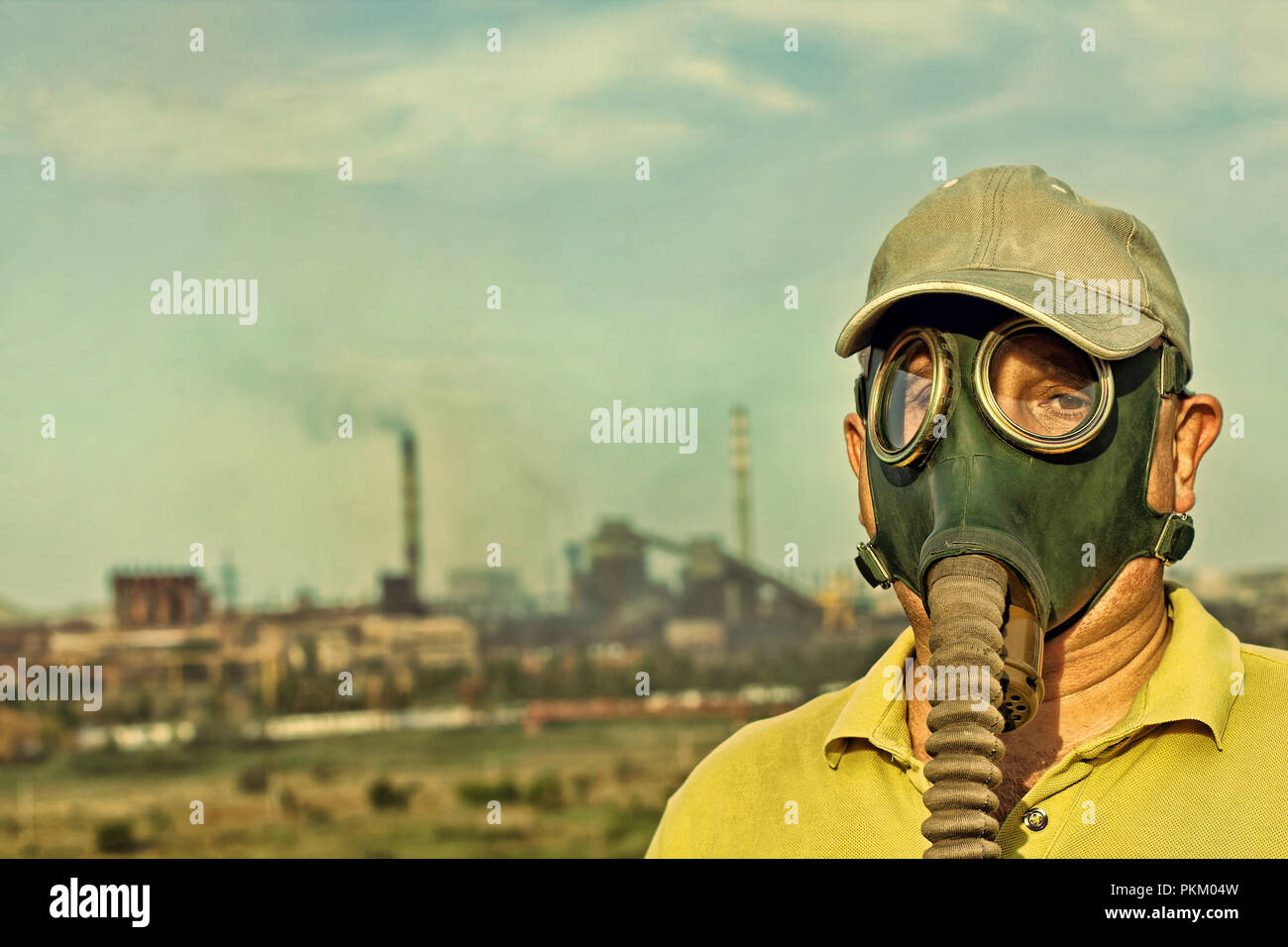 Men in gas mask looks at camera against the industrial factory and ...