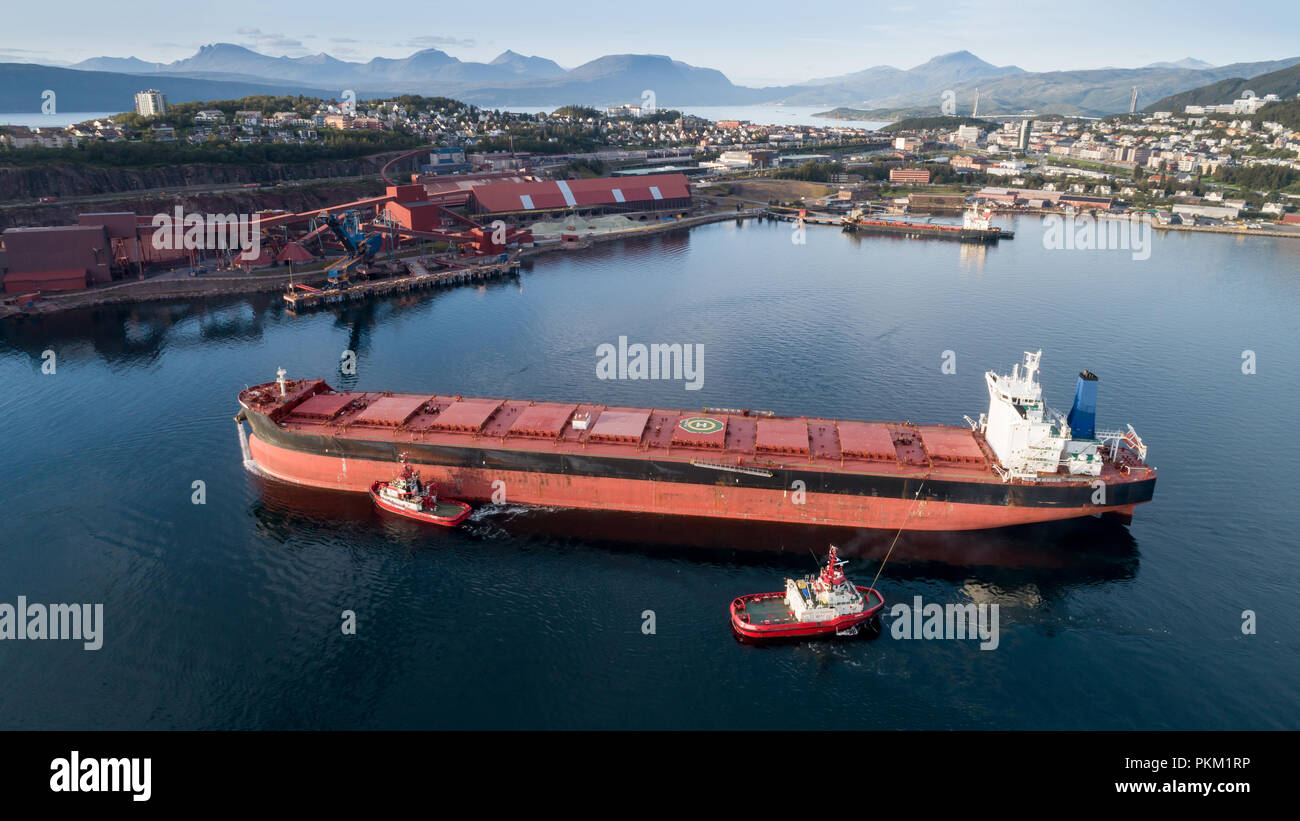 Aerial shot of a cargo ship approaching port terminal with help of ...