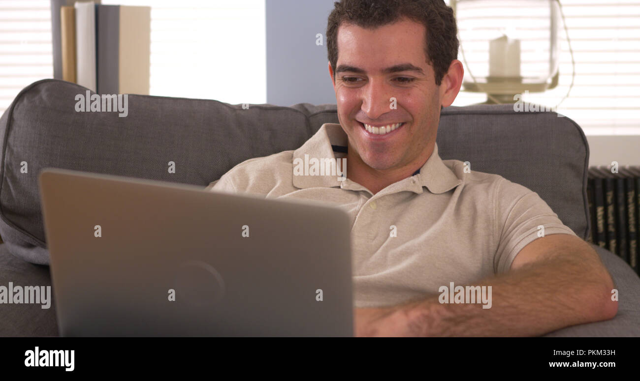 Happy man using laptop on couch Stock Photo - Alamy