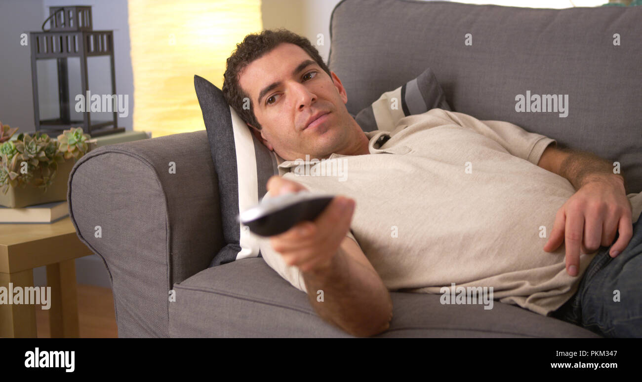 Man flipping through channels on couch Stock Photo - Alamy