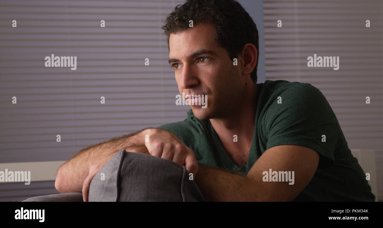 Guy sitting on couch thinking Stock Photo - Alamy