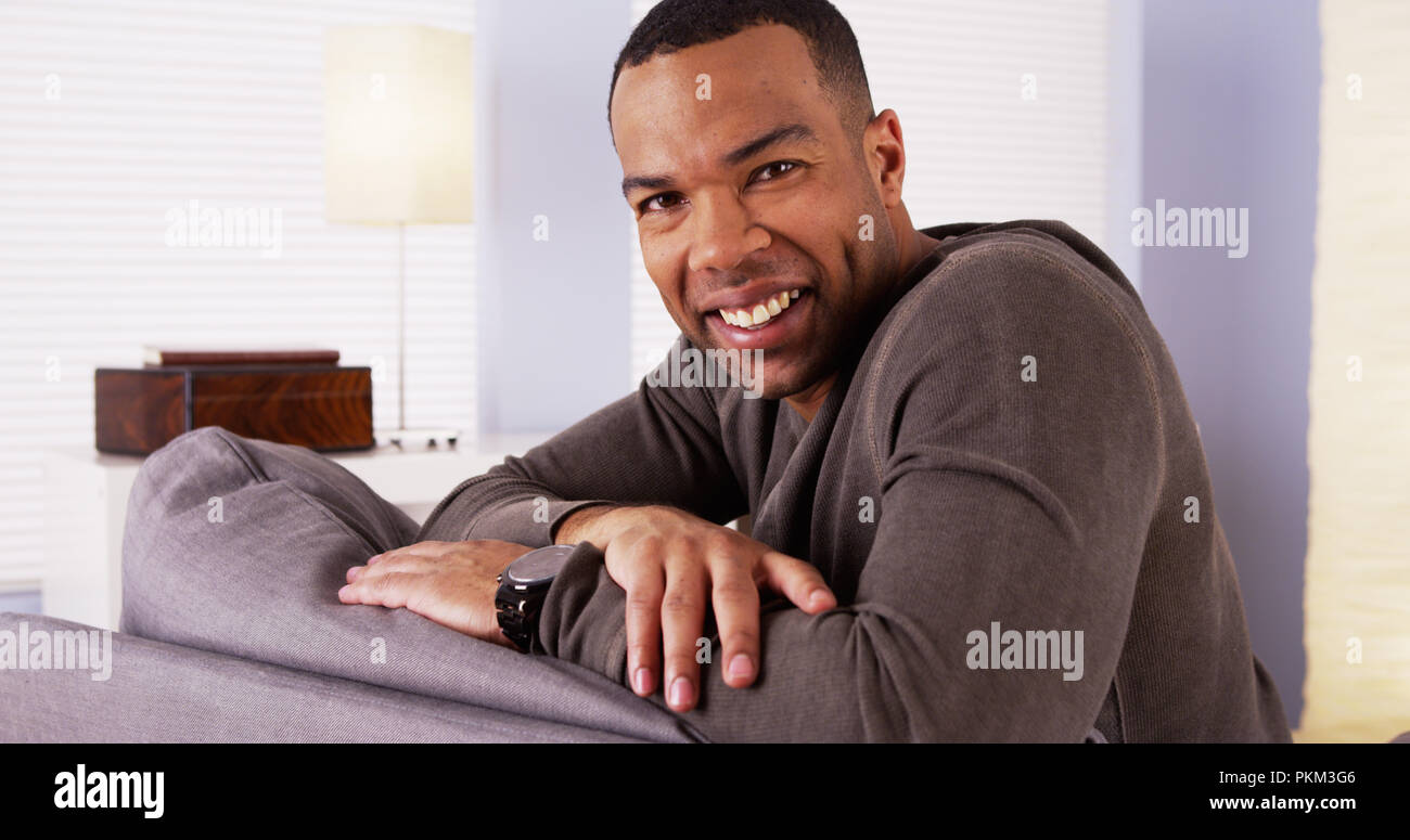 Handsome African man sitting on couch Stock Photo - Alamy