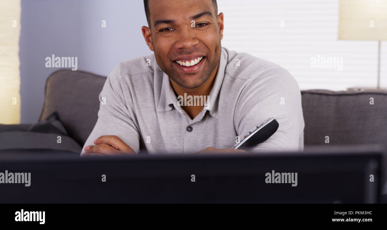 Black man flipping through channels on TV Stock Photo - Alamy
