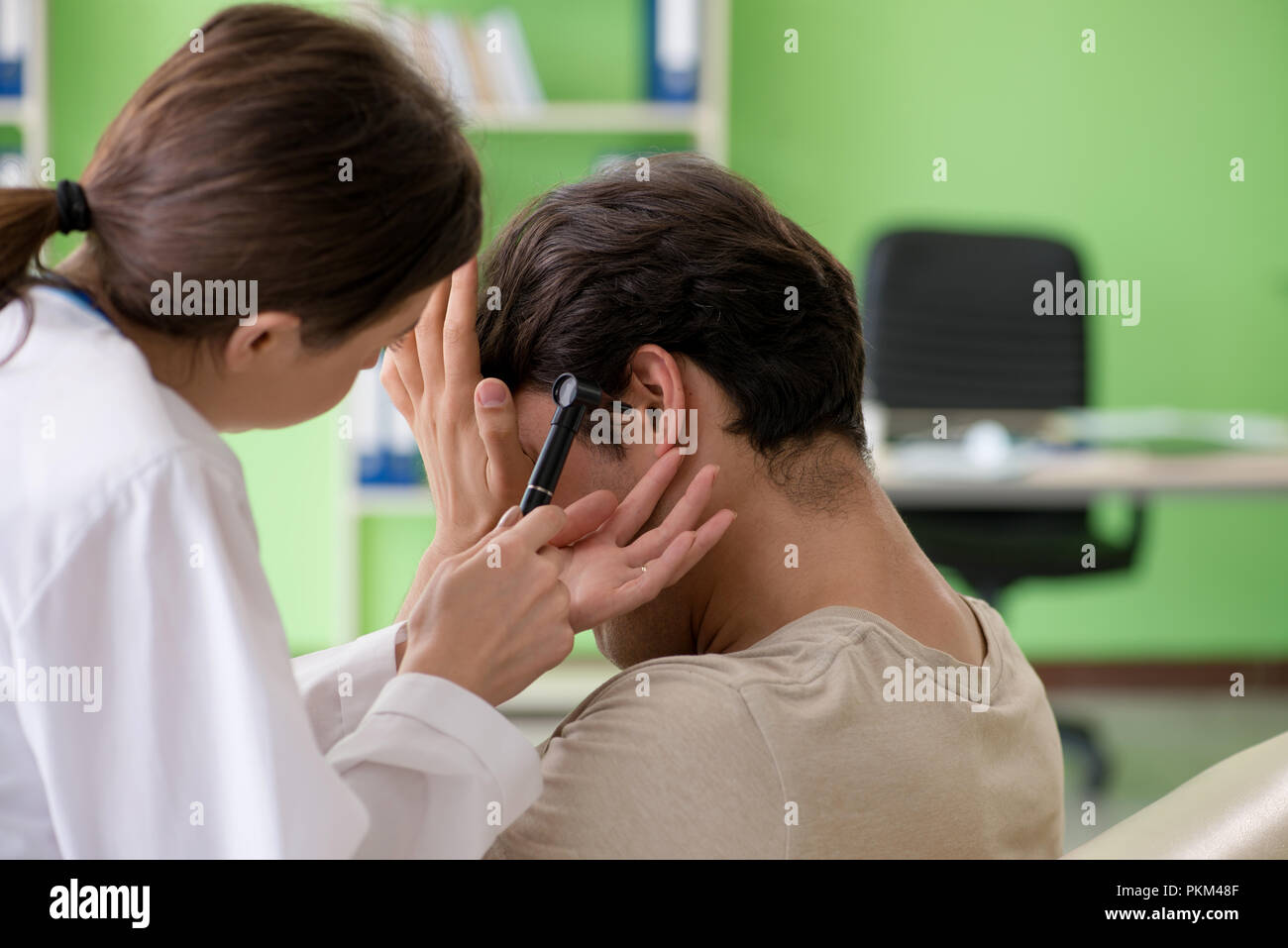 Female doctor checking patient's ear during medical examination Stock ...
