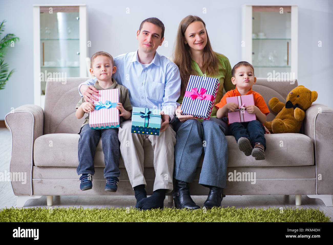 Young parents giving out Christmas gifts at home Stock Photo - Alamy