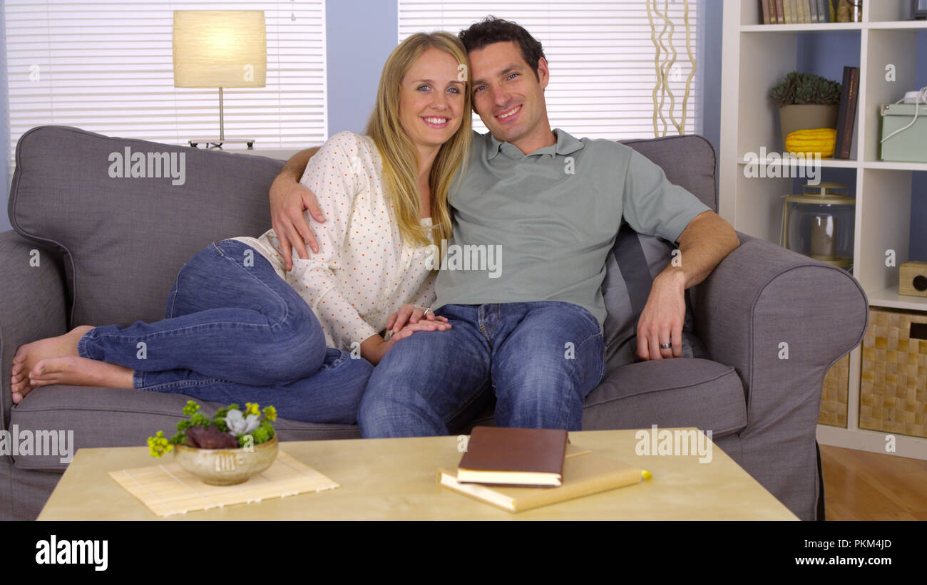 Couple cuddling on couch Stock Photo - Alamy