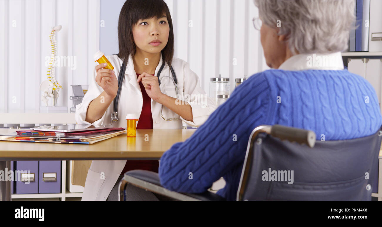 Asian doctor explaining prescription to elderly patient Stock Photo - Alamy