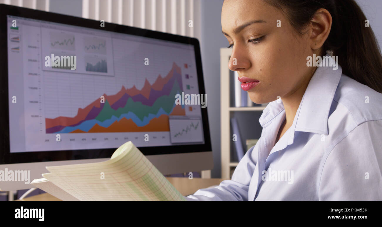 Mexican businesswoman writing notes by computer Stock Photo - Alamy
