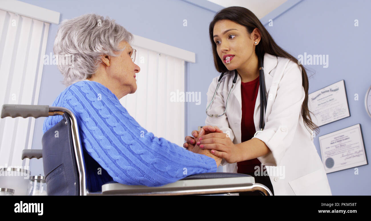 Hispanic woman doctor comforting disabled elderly patient Stock Photo ...