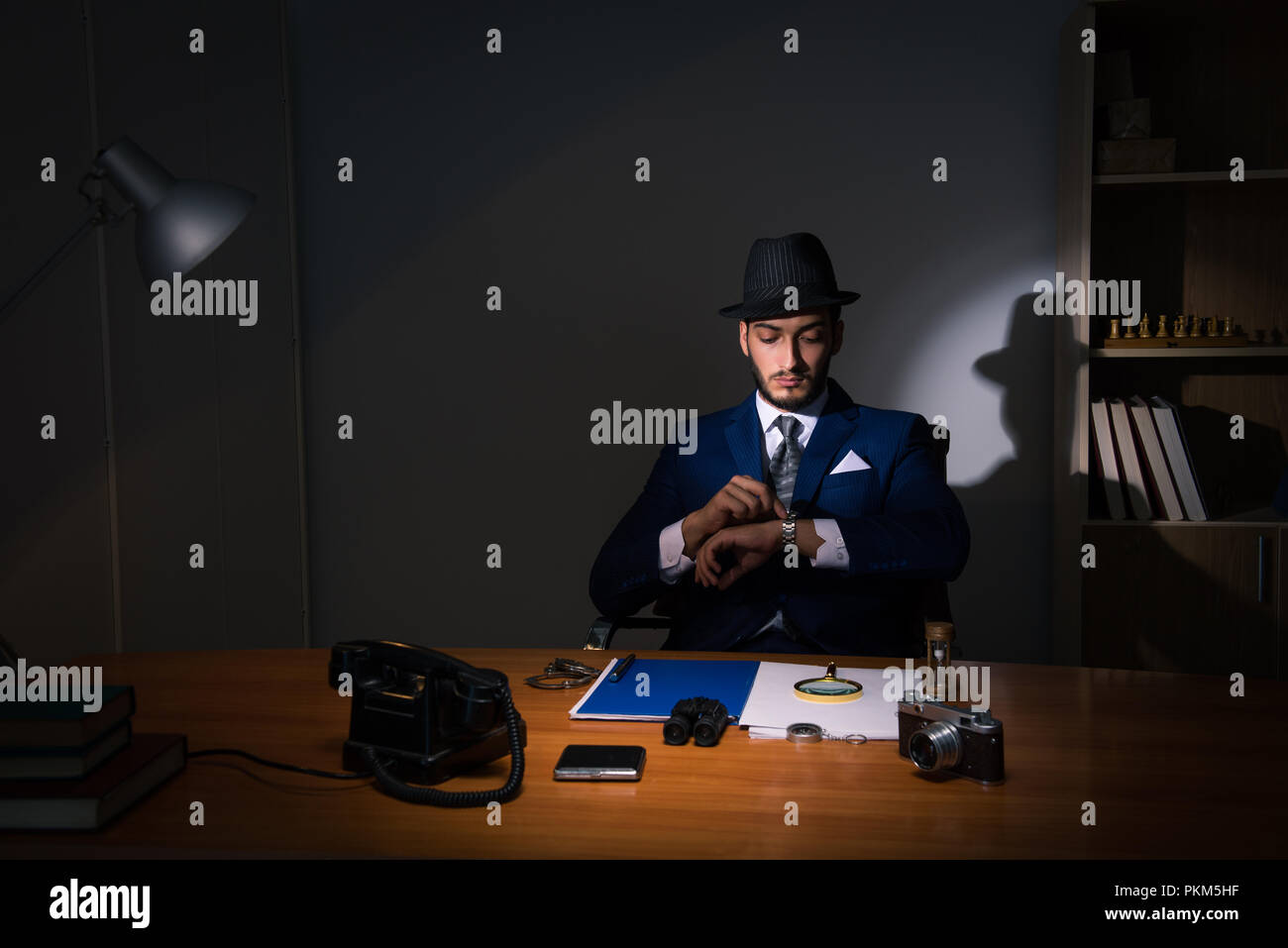 Detective sitting in dark room in vintage concept Stock Photo - Alamy