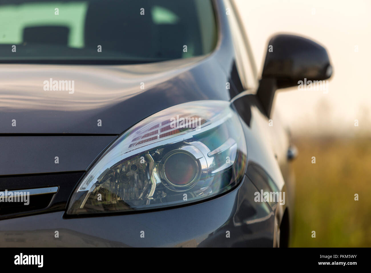 Close-up detail part of black shiny car-headlight, mirror, hood and ...