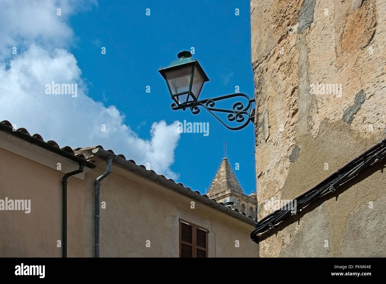 Mallorca buildings with tiles, tower, old wrought iron wall lamp and ...