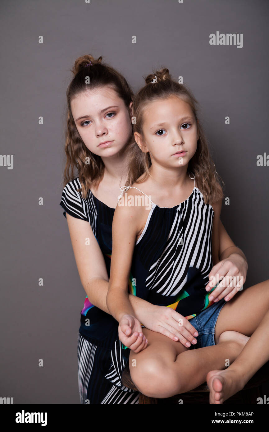 two sisters girls portrait on a grey background Stock Photo - Alamy