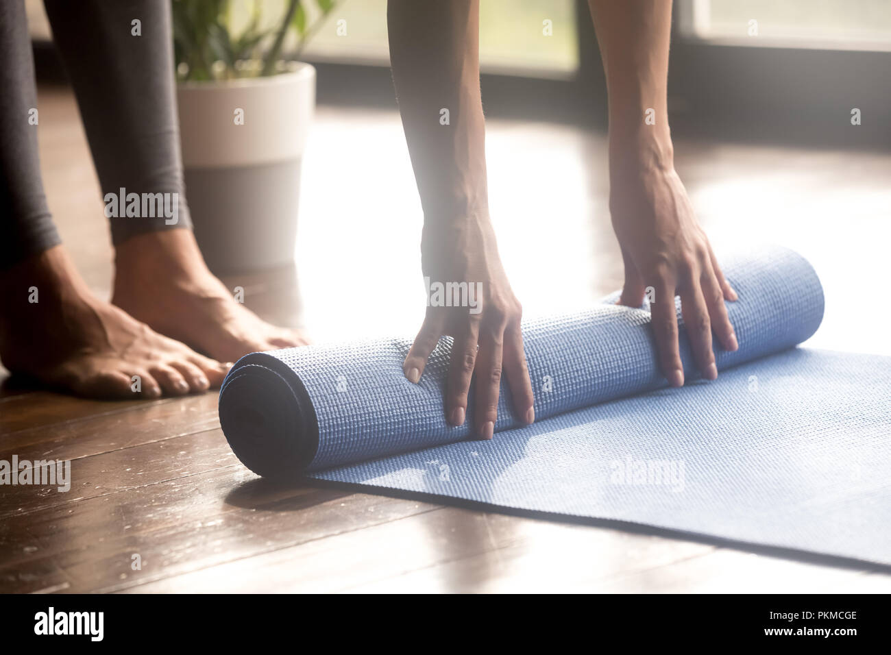Woman unrolling blue yoga mat, legs close up Stock Photo - Alamy