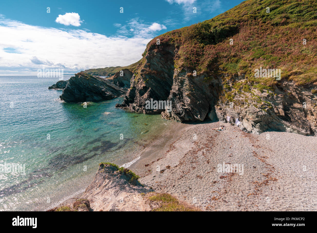 One person sunbathing on a small cove beach at Lantivet Bay, Cornwall ...