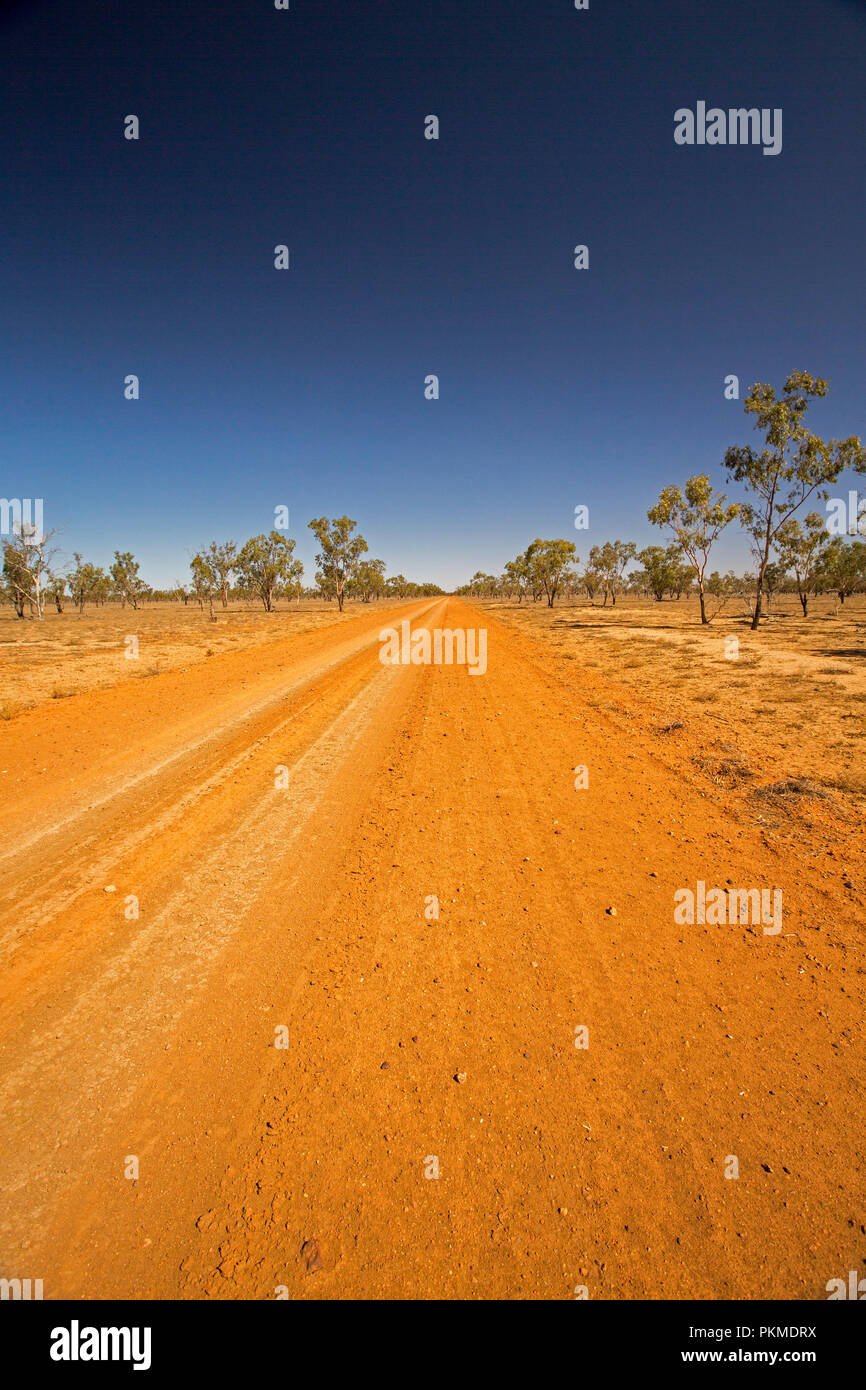 Red Australian outback road slicing through arid landscape with sparse ...