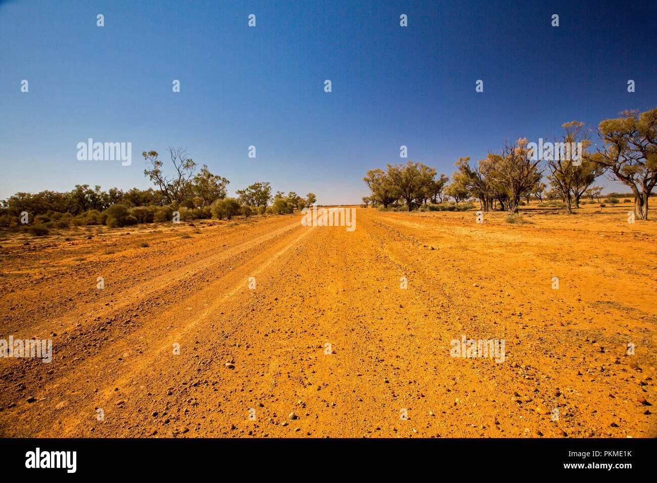 Red Australian outback road slicing through arid landscape with sparse ...
