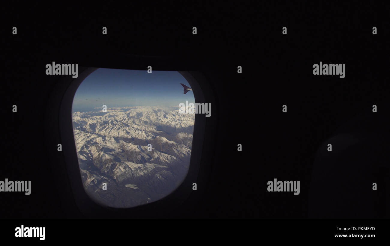 Mountain range with snow from the airplane window. Airplane wing ...