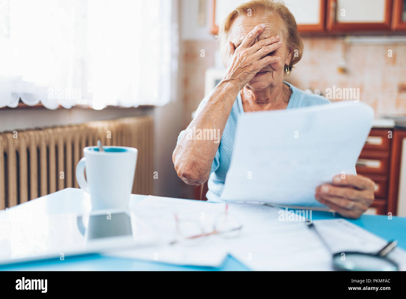Elderly woman looking at her utility bills and paperwork Stock Photo ...
