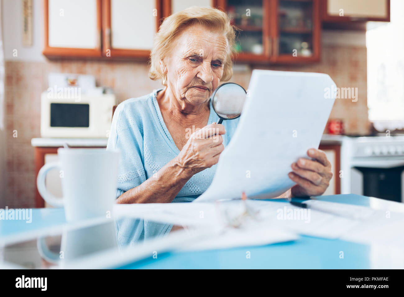 Elderly woman looking at her utility bills and paperwork Stock Photo ...