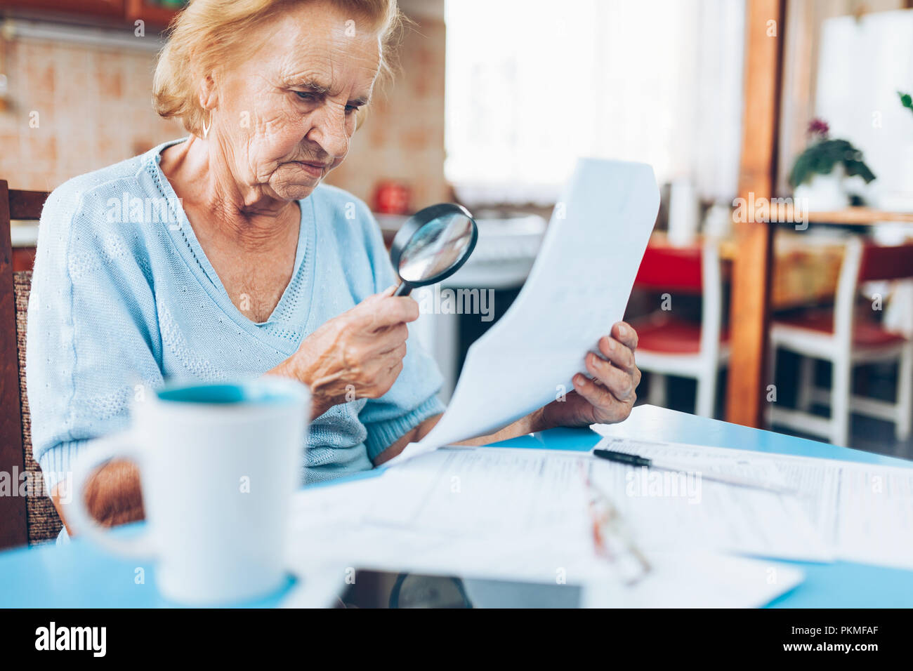 Elderly woman looking at her utility bills and paperwork Stock Photo ...