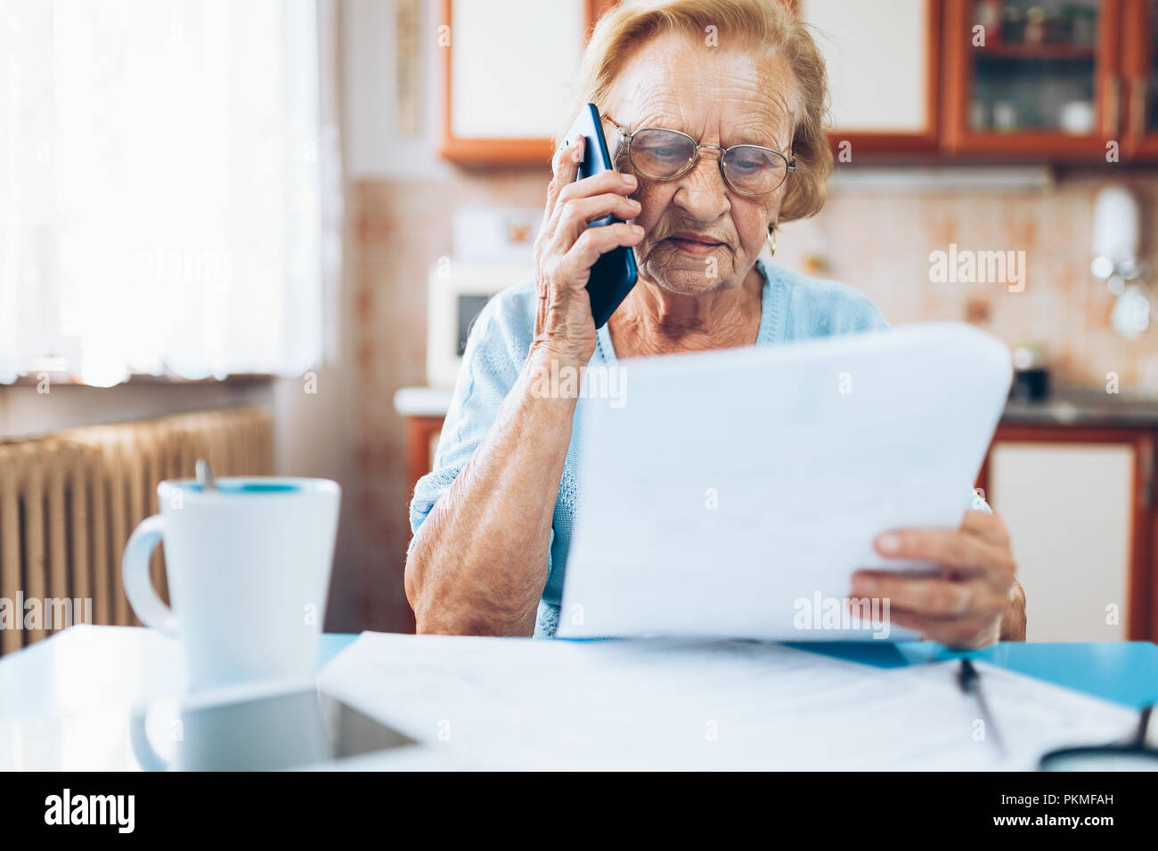 Elderly woman at home contacting custumer services after recieving a ...
