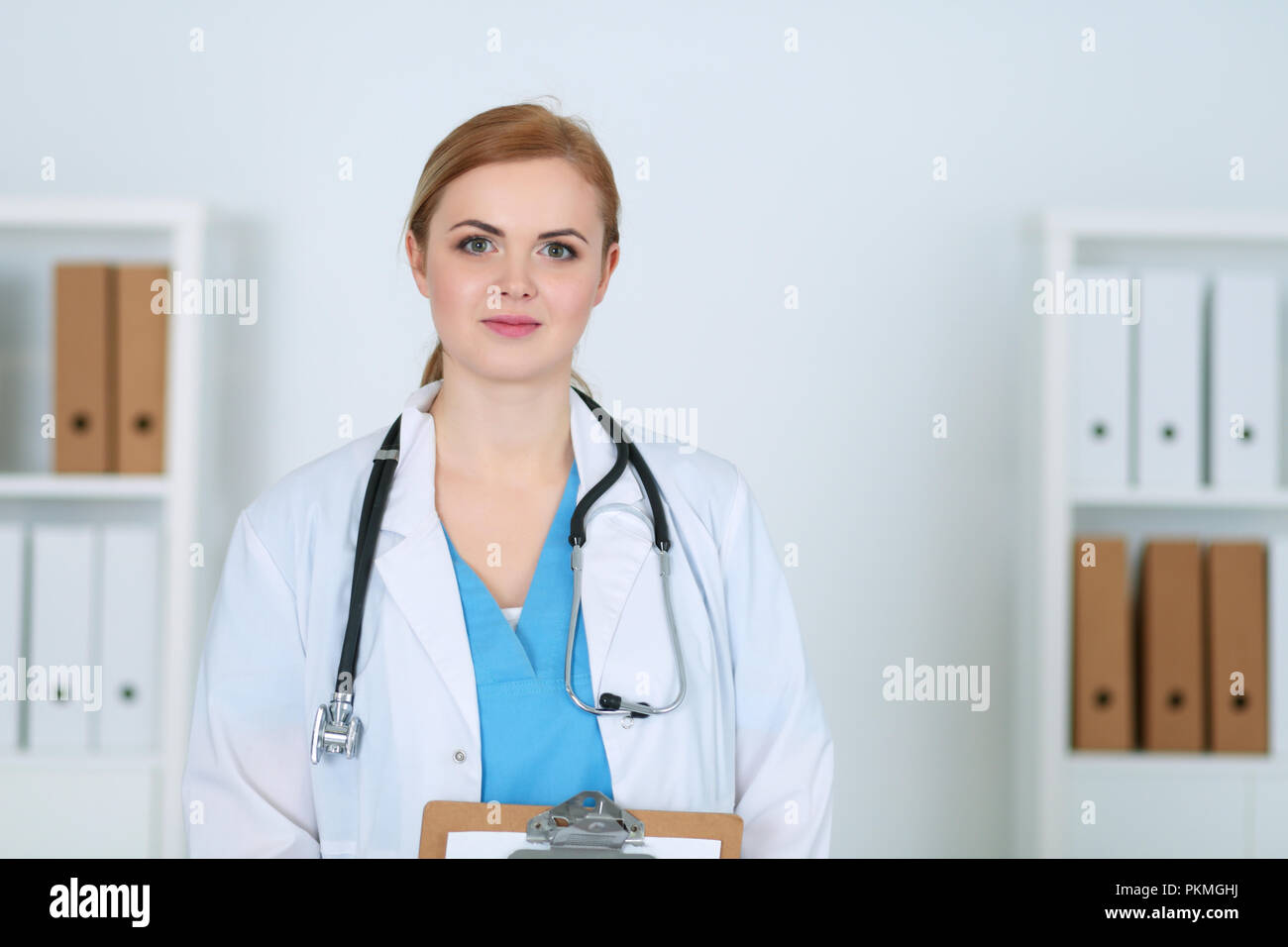 Beautiful female medical doctor standing at hospital. Physician is ...