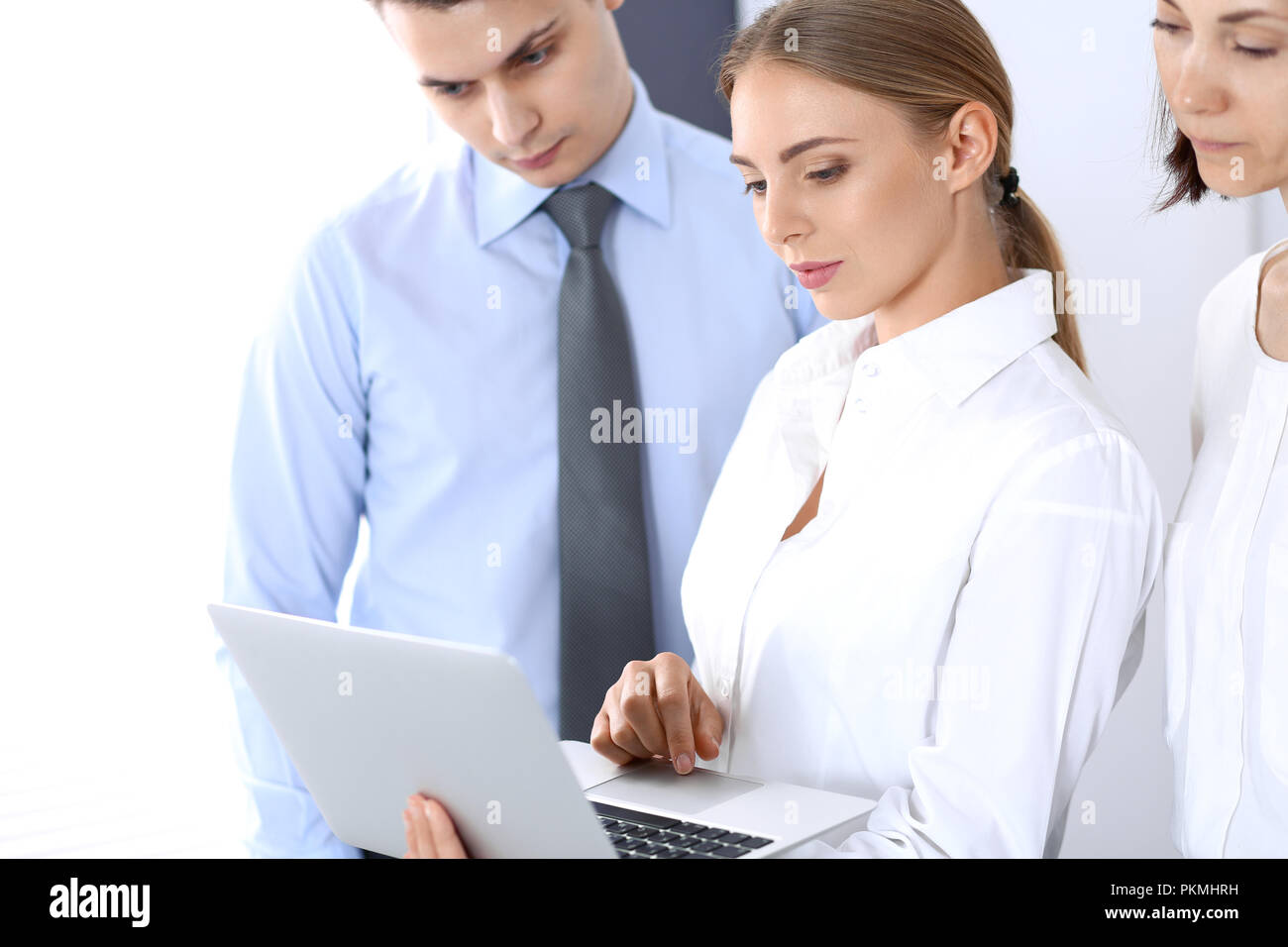 Group of business people using laptop computer while standing in office ...