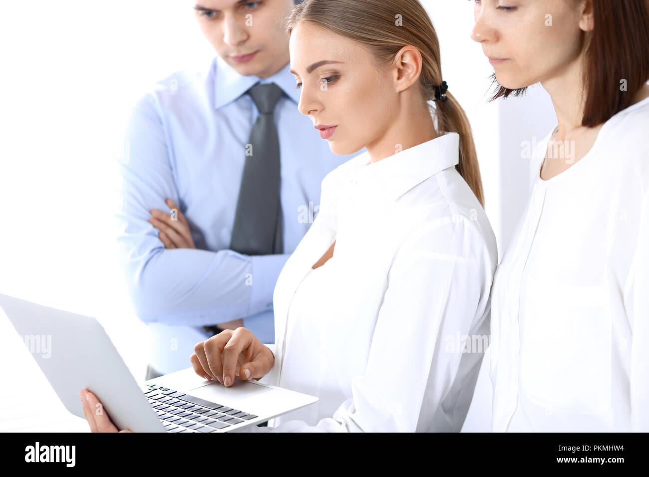 Group of business people using laptop computer while standing in office ...
