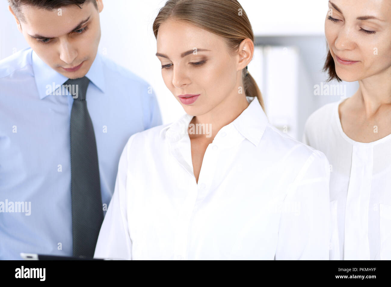 Group of business people using laptop computer while standing in office ...