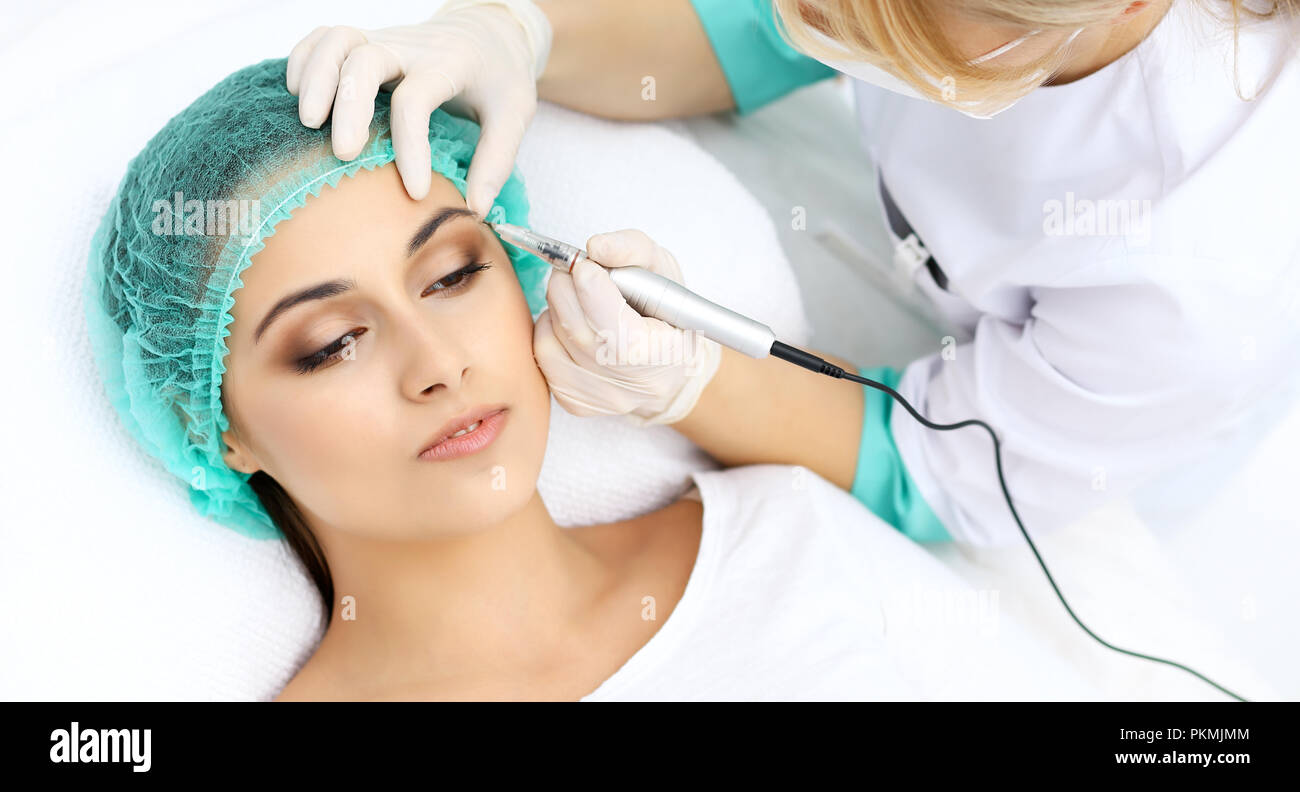 Professional beautician doing eyebrow tattoo at woman face. Permanent ...