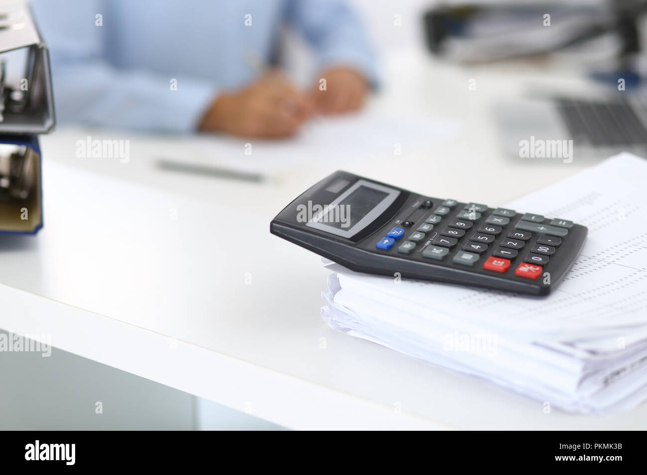 Calculator and binders with papers are waiting to be processed by ...