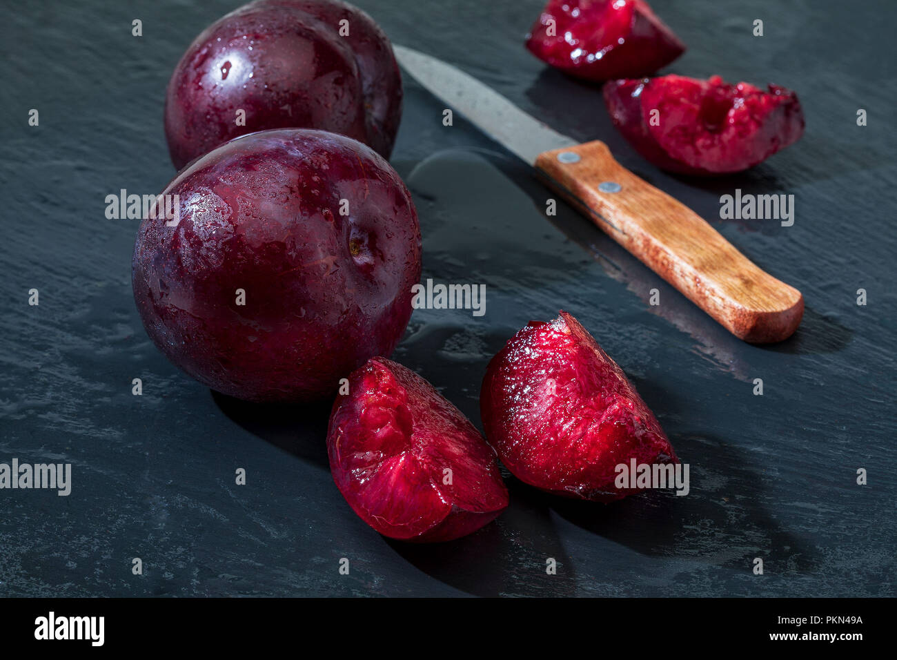 Appetizing and healthy red plums, whole and cut into segments with a ...