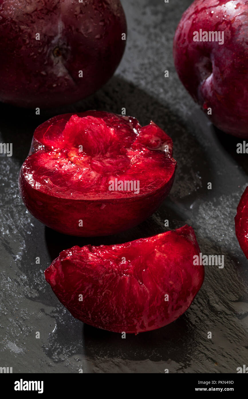 Appetizing and healthy red plums, whole and cut into segments with a ...