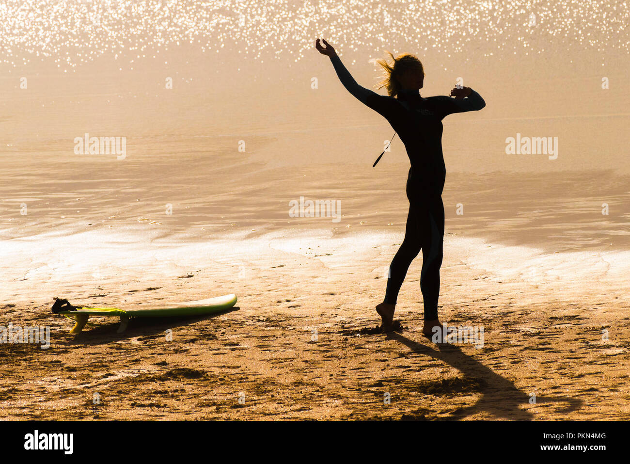 The silhouette of surfer stretching and exercising on Fistral Beach ...