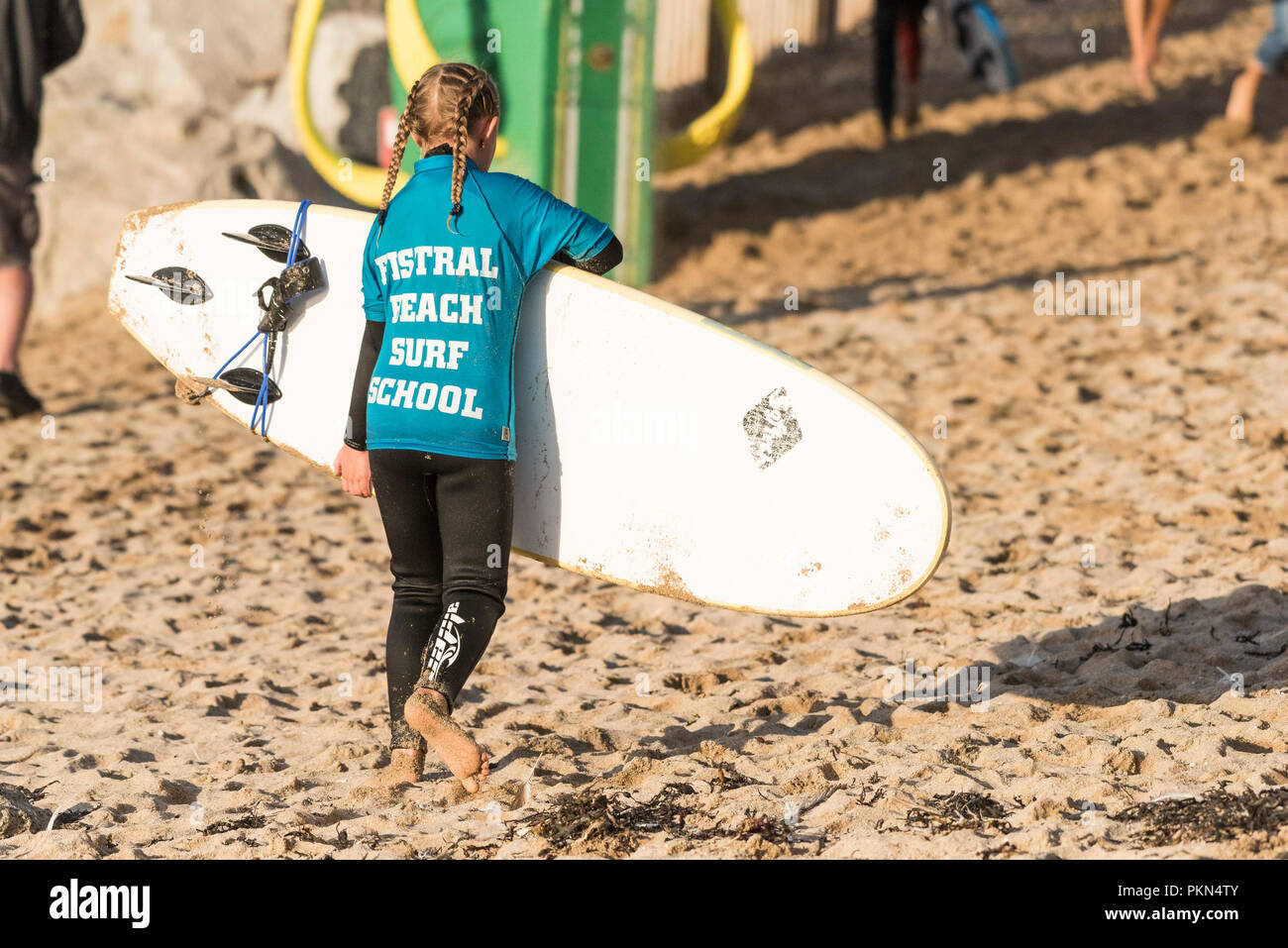 A young girl returning her surfboard after a surf lesson with Fistral ...