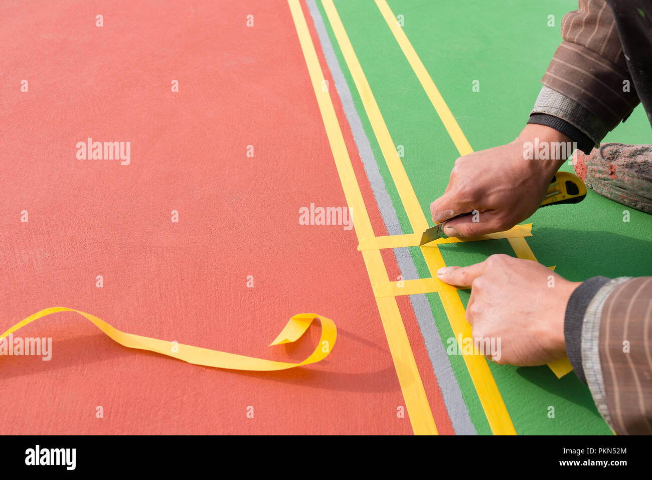 workers taping and marking the sideline on the floor for an outdoor ...