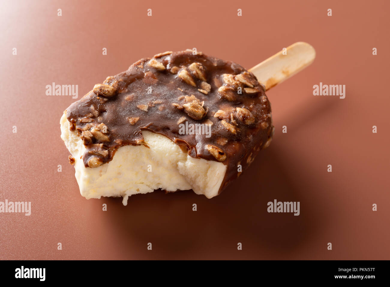 side view chocolate outer ice cream with peanuts on a brown background ...