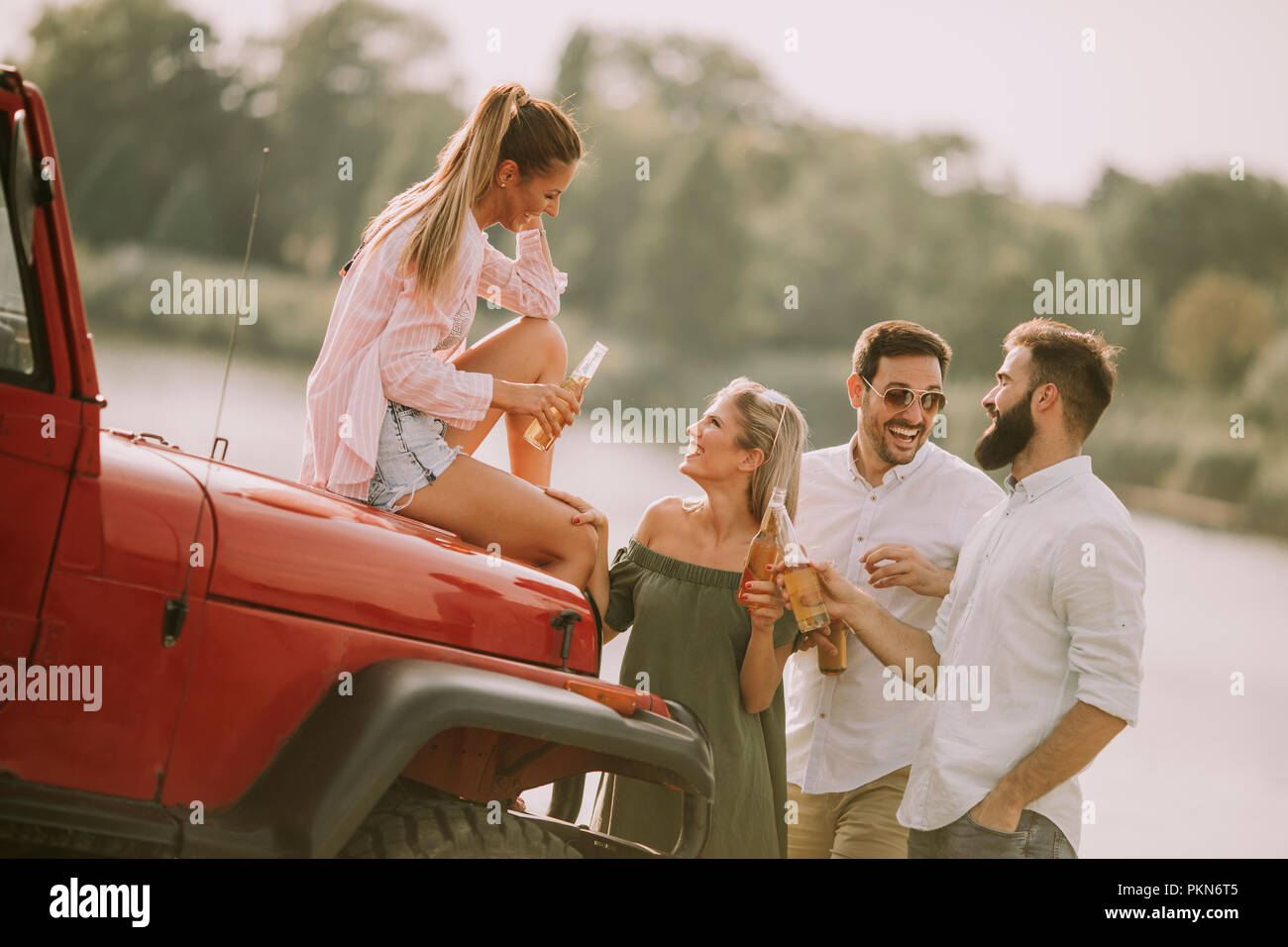 Four young people having fun in convertible car by river Stock Photo ...