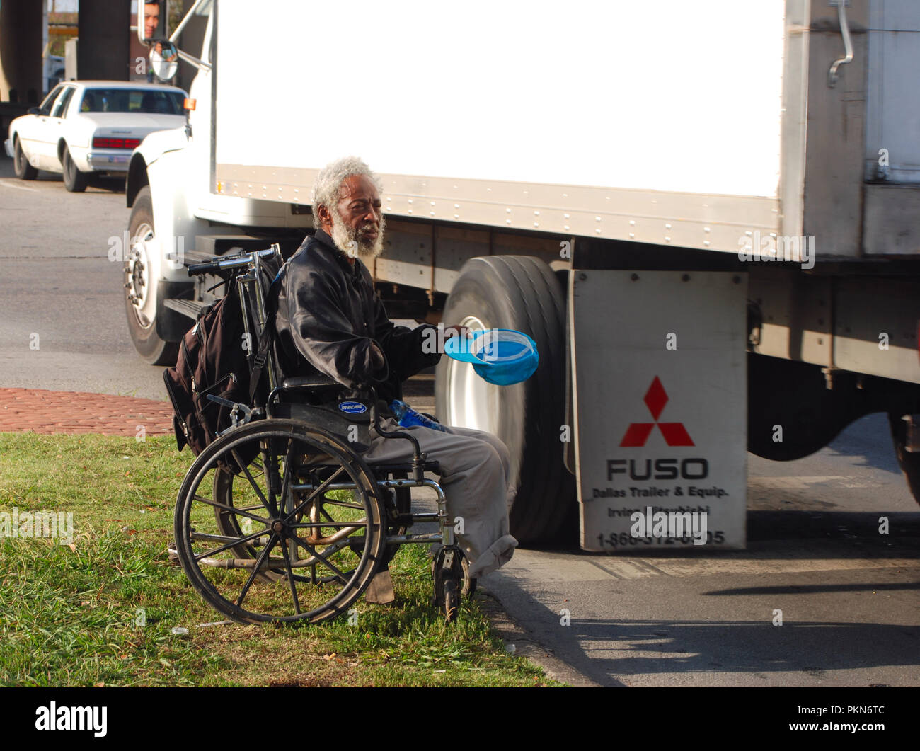 Harold, an African American man, panhandling along side a busy street ...