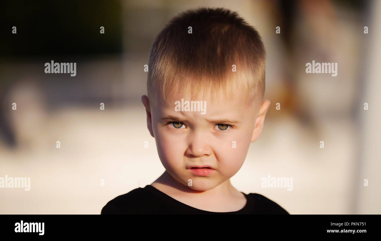 A beautiful little boy looks at the camera. The sun shines Stock Photo ...