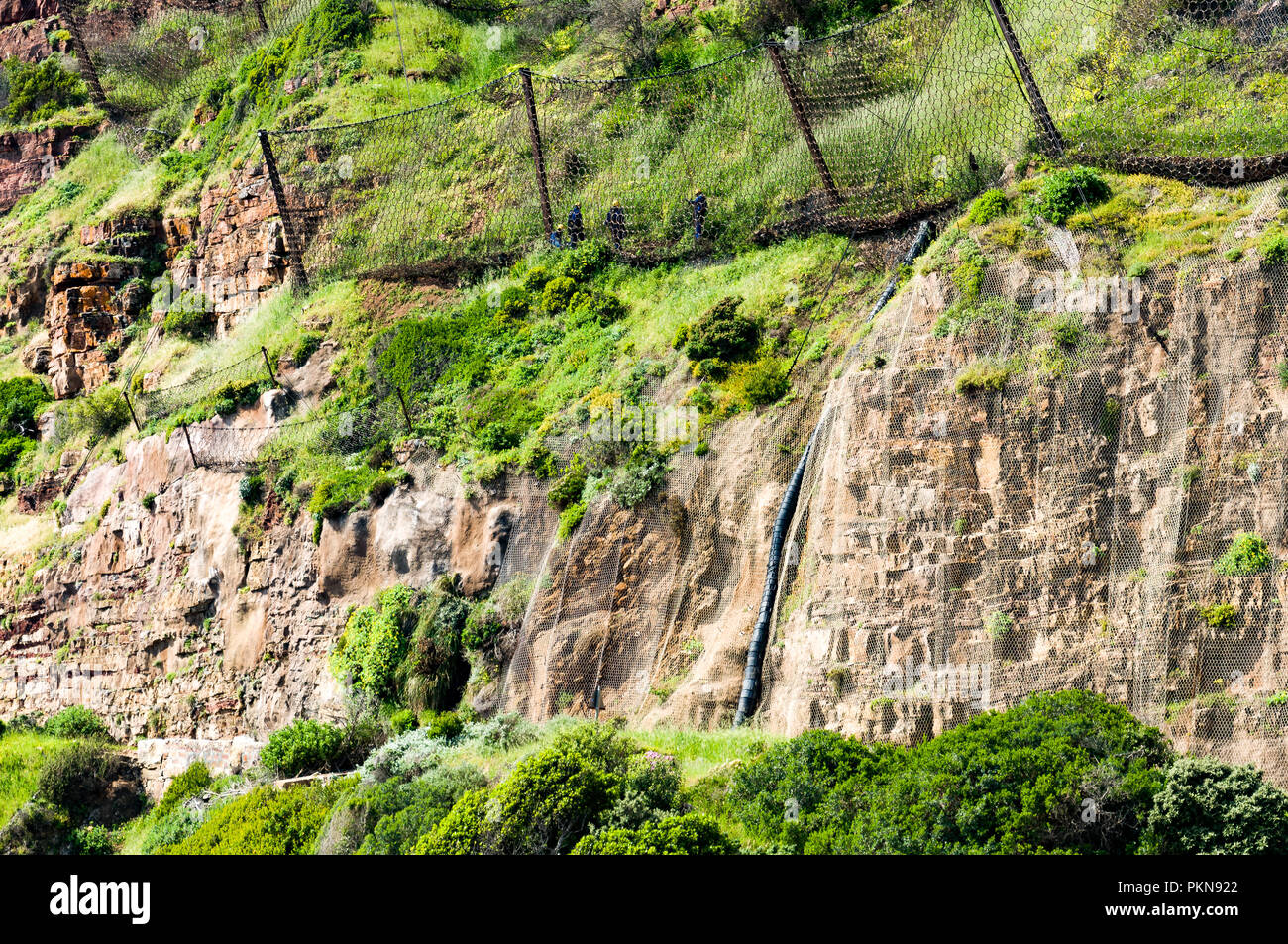 Workers making safety nets to prevent rock falls onto the road at ...