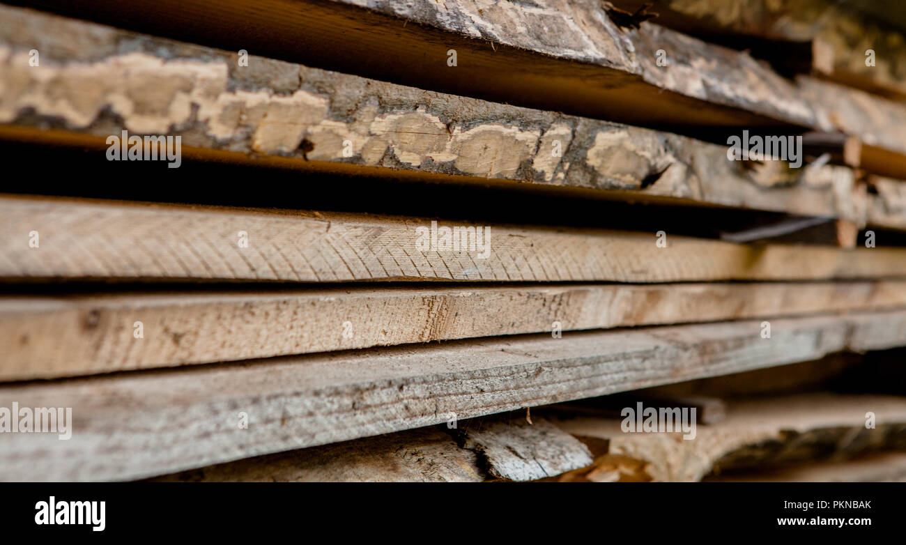 Folded wooden brown and gray planks in a sawmill. Piled alder boards as ...