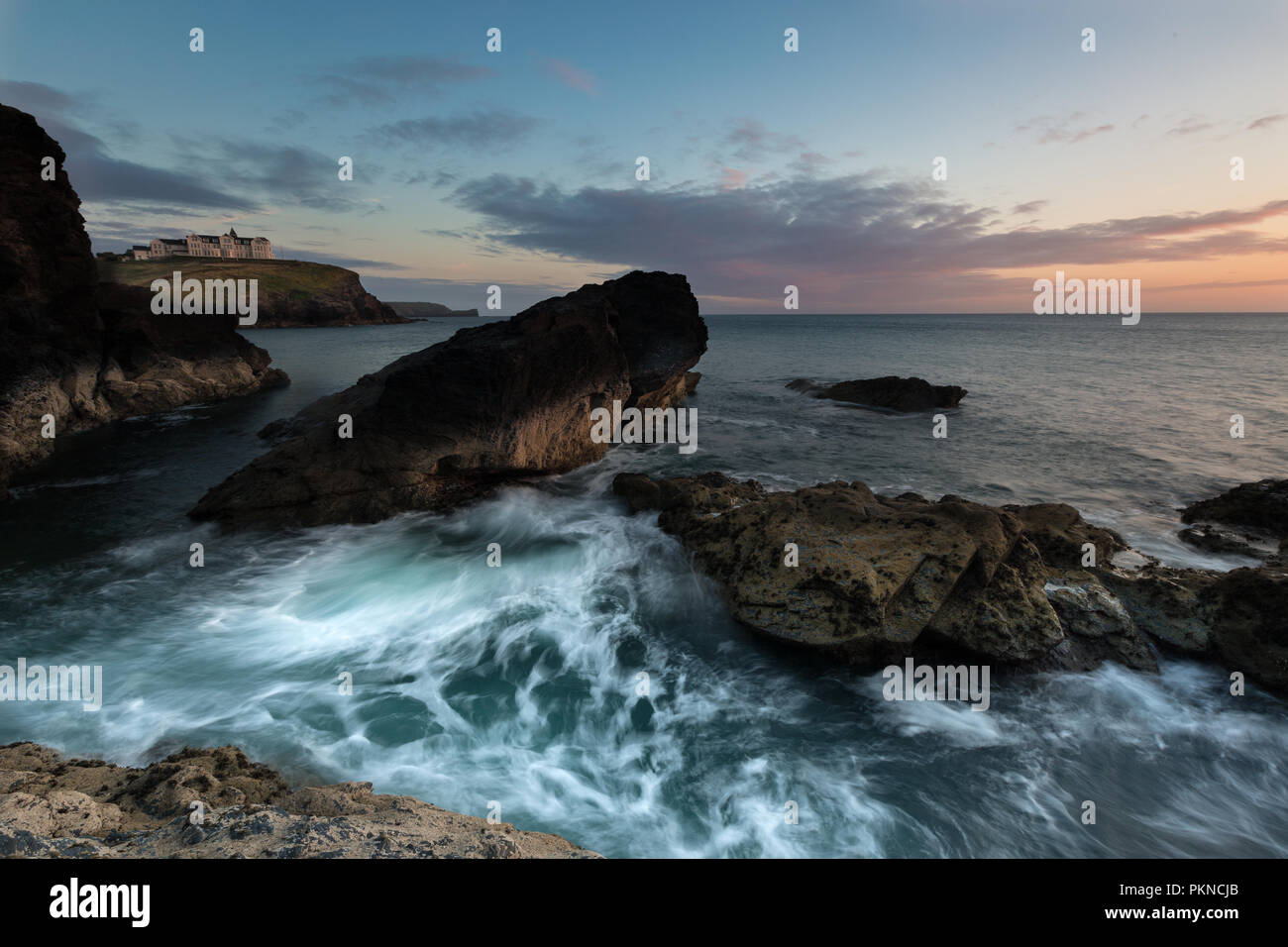 A rugged coastal sunset image of crashing waves flowing over harsh ...