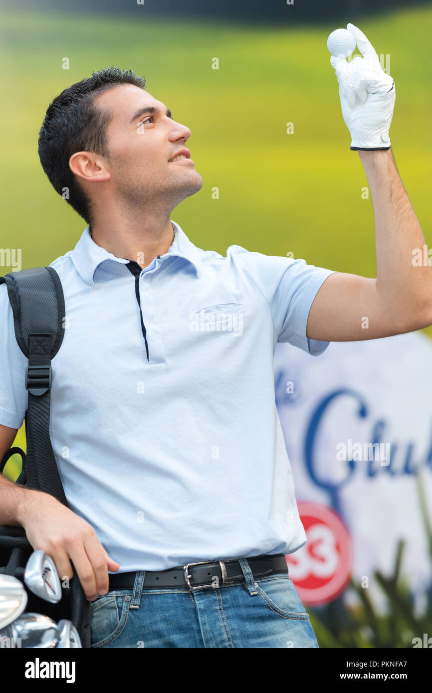 golfer holding ball and golf club Stock Photo - Alamy